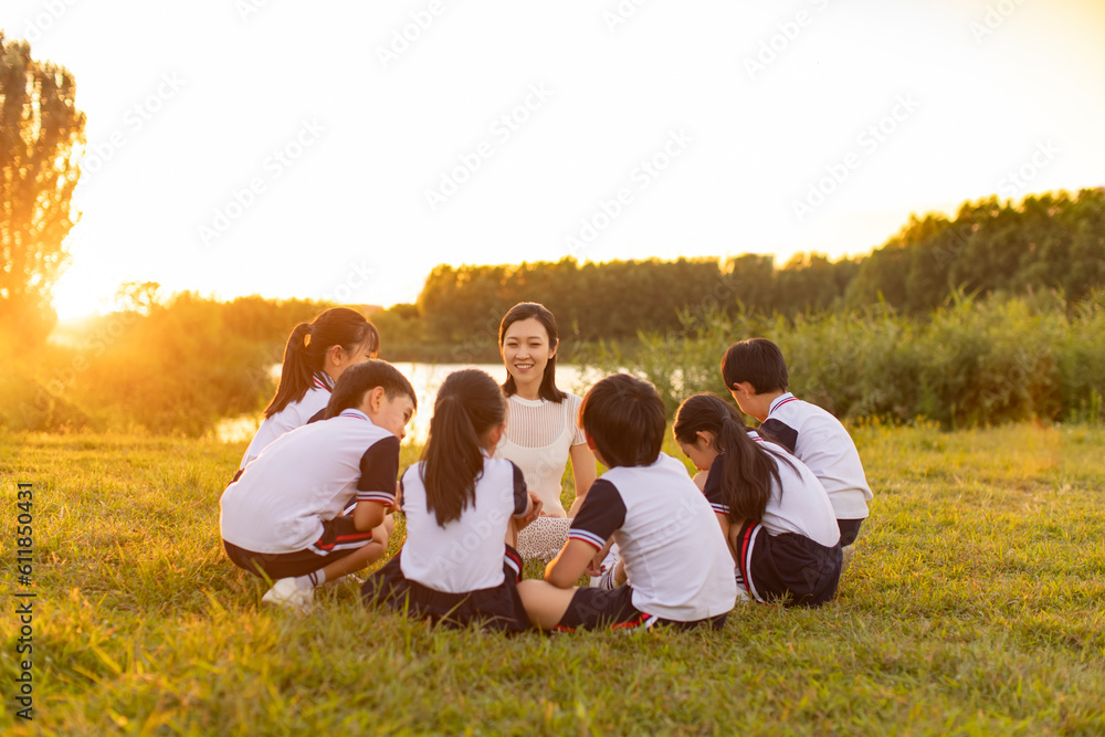 Cheerful school children relaxing in park with their teacher Stock ...