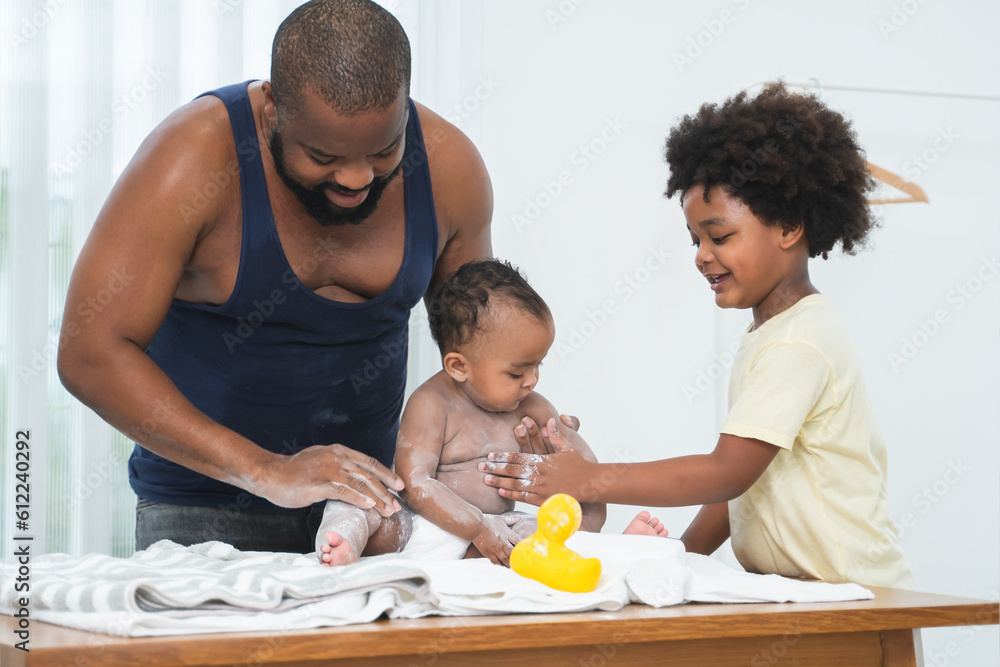 African middle aged father and child boy applying dusting powder on ...