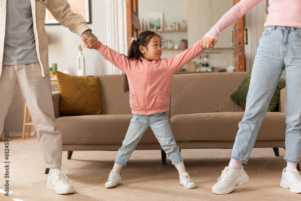 Asian parents pulling daughter's hands in different directions standing ...
