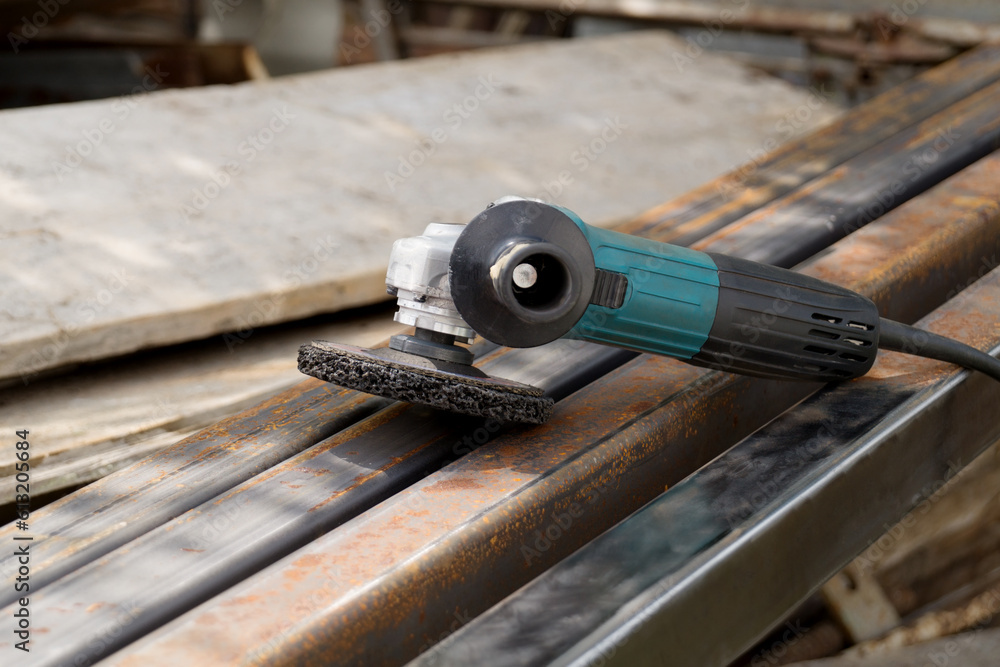 Not new electric angle grinder tool lies on a rust metal square tube ...