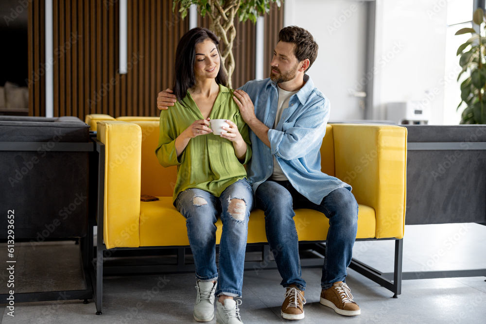 Man kindly supports her woman while sitting together on a couch at ...