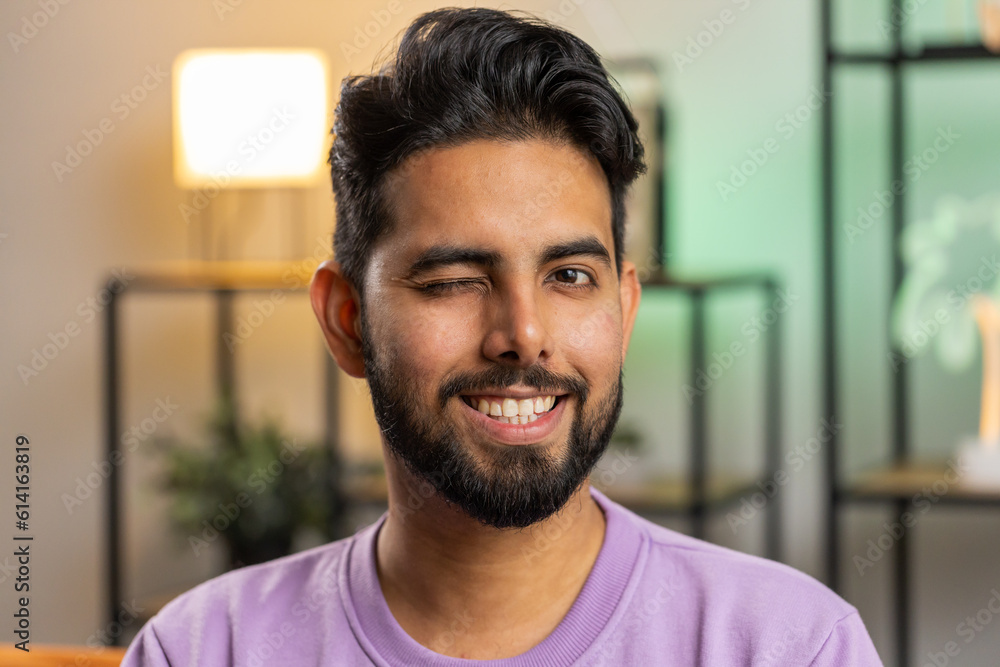 Smiling playful happy young indian man blinking eye, looking at camera ...