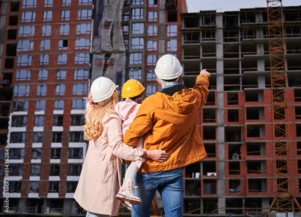 Back view of man pointing at apartment building under constructing ...