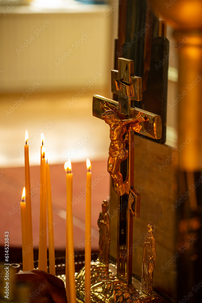 Gold cross with prayer candles lit inside of an old church in Alaska ...