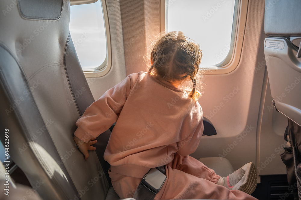 Cute little girl traveling by an airplane. Child sitting by aircraft ...