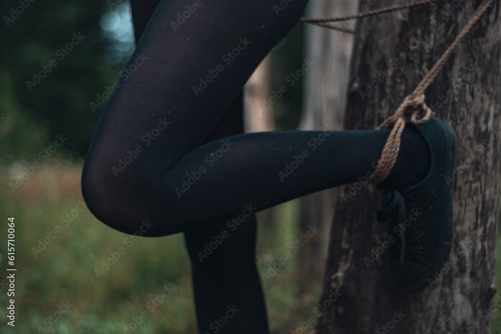 tied up legs of a woman in green body and black tights with a natural ...