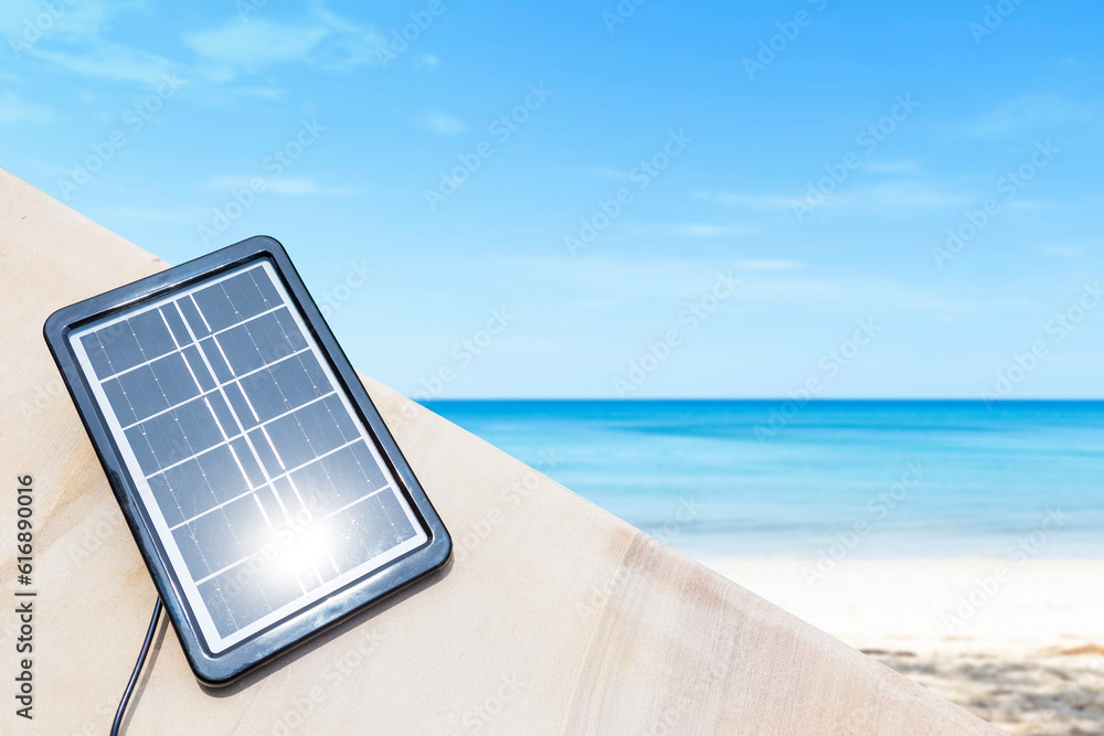 Portable solar cell panel over beautiful beach background, green energy ...