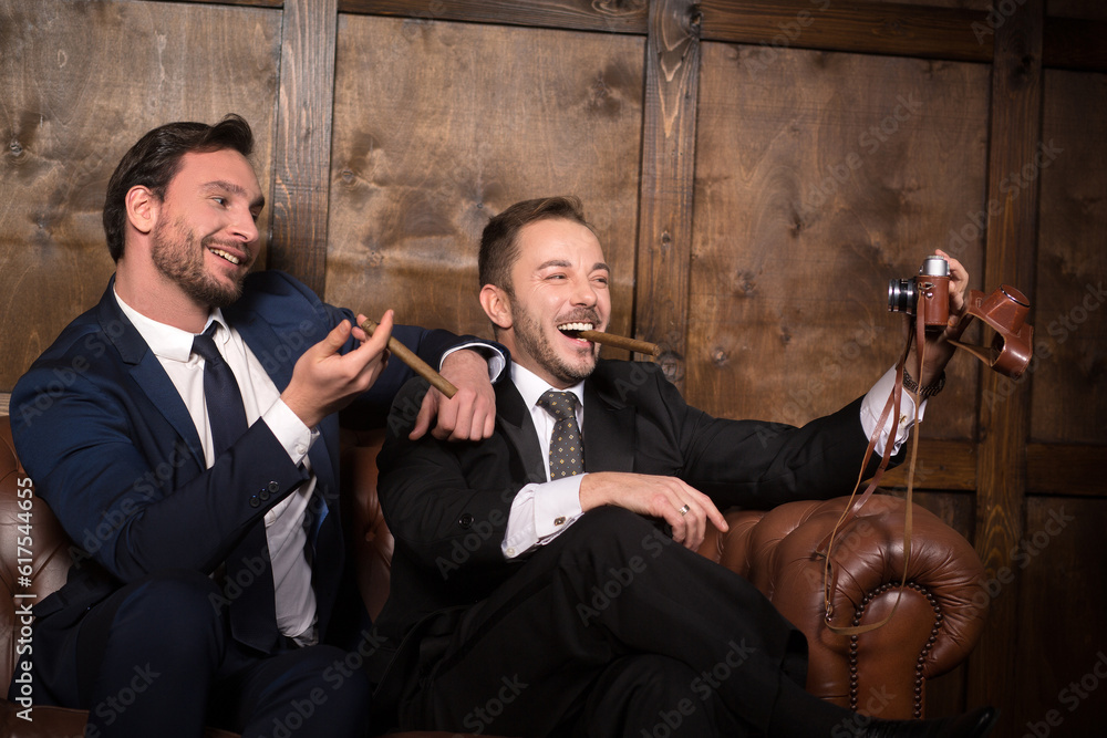 Rich businessmen making self photos while sitting on sofa in restaurant ...
