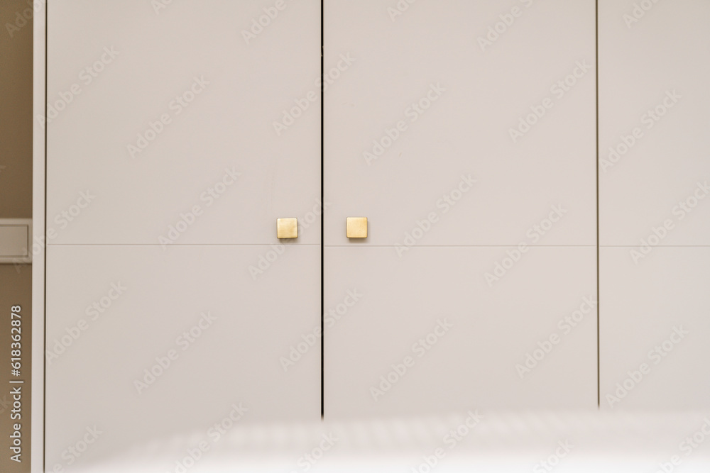 two white cupboards with gold handles and knobs in a room that has no ...