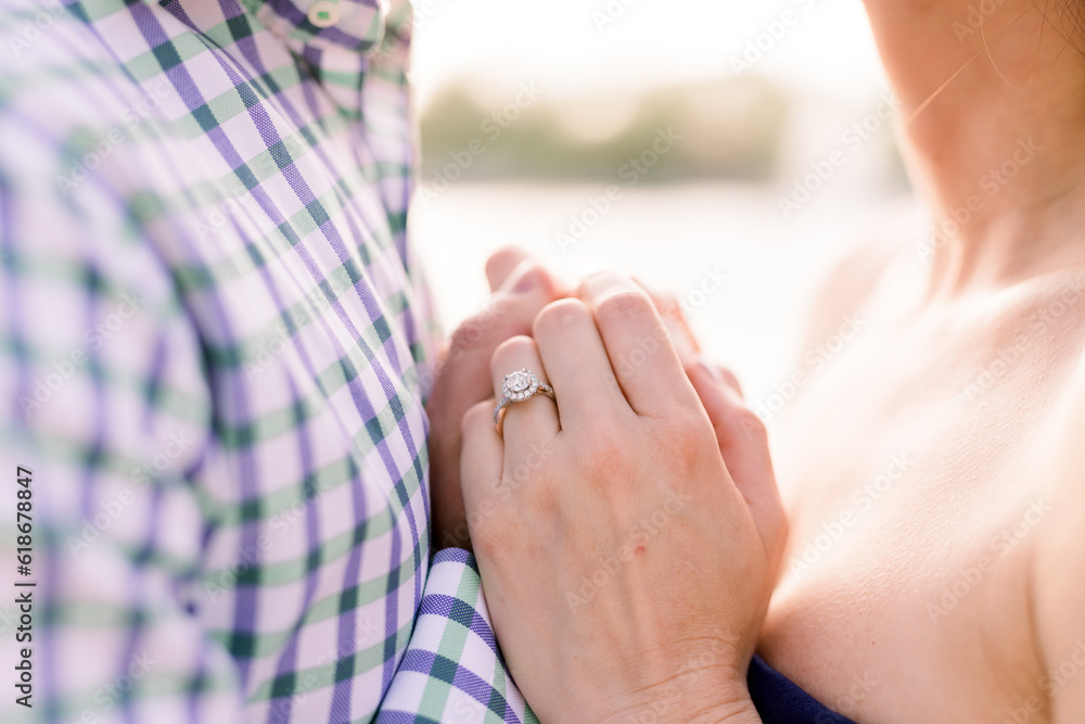 Engaged couple stand with their hands clasped together showing off the ...