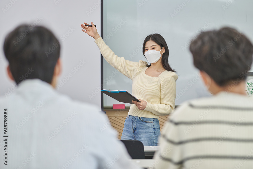 An Asian female student or professor is wearing a mask and standing in ...