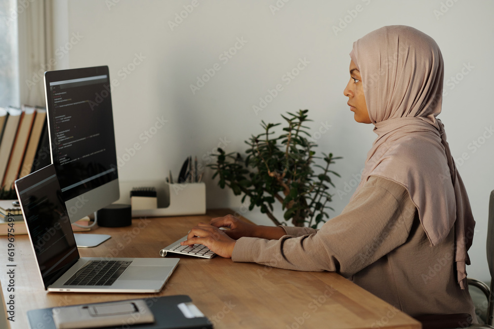 Young Muslim businesswoman in hijab decoding data on computer screen ...