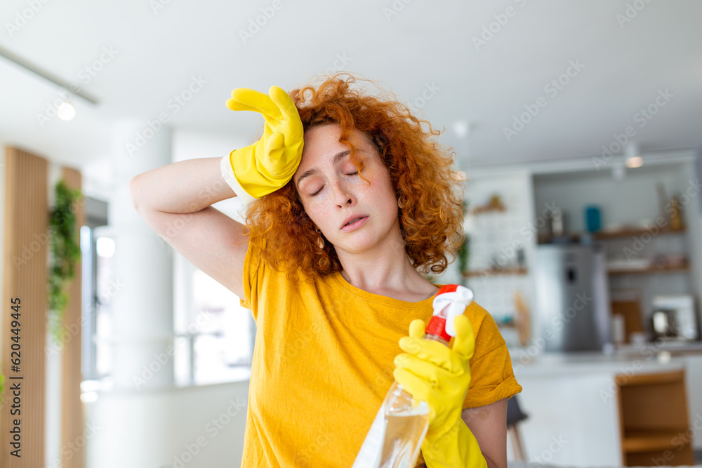 Red-haired woman wearily cleans, fatigue evident on her face. With ...