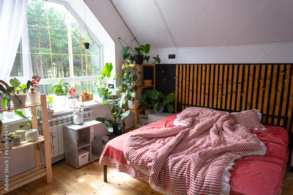 Unmade bed with red striped linen and a mess in Loft style bedroom ...