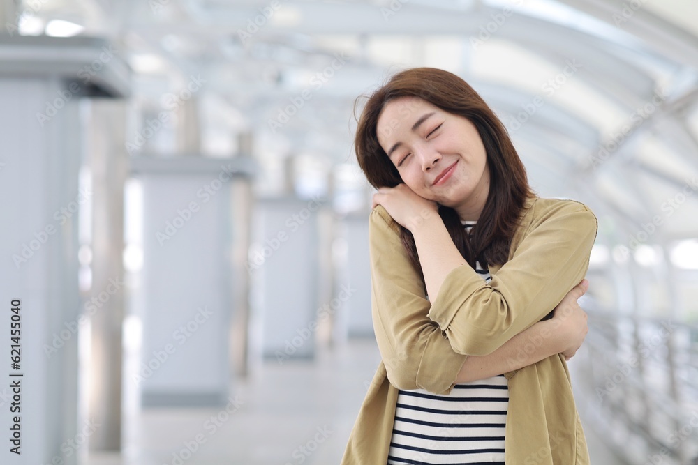 Beautiful Asian woman in casual style standing hugging herself ...