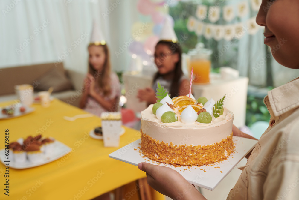 Cropped image of smiling birthday boy bringing cake with candle to ...
