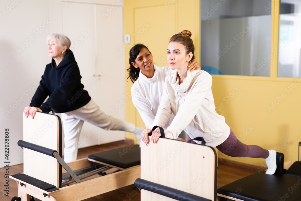 Two health conscious women of different ages perform a Pilates exercise ...