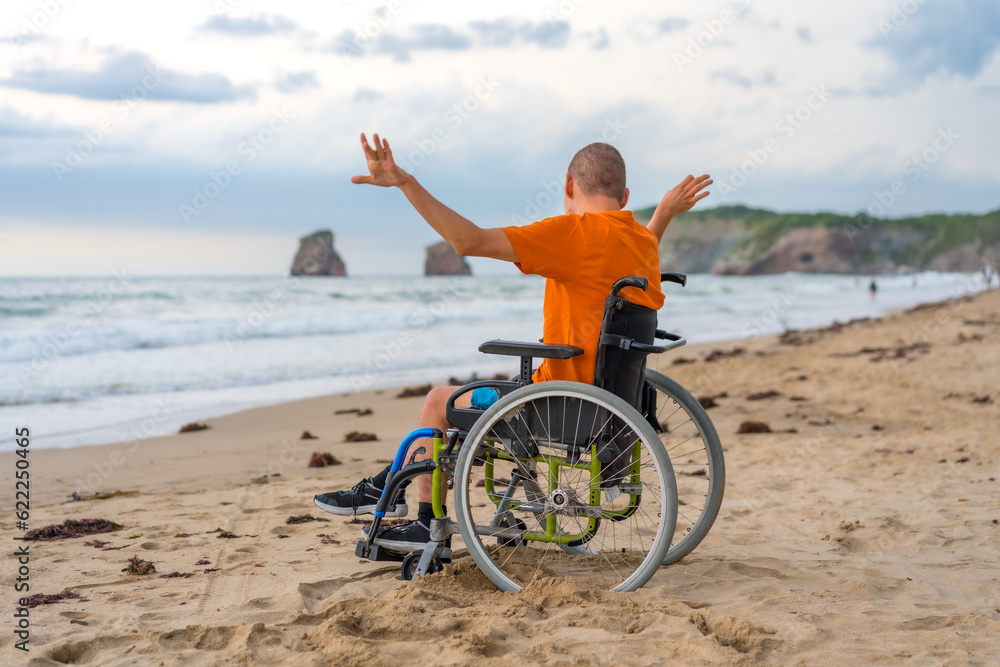 Portrait a disabled person on his back in a wheelchair on the beach ...
