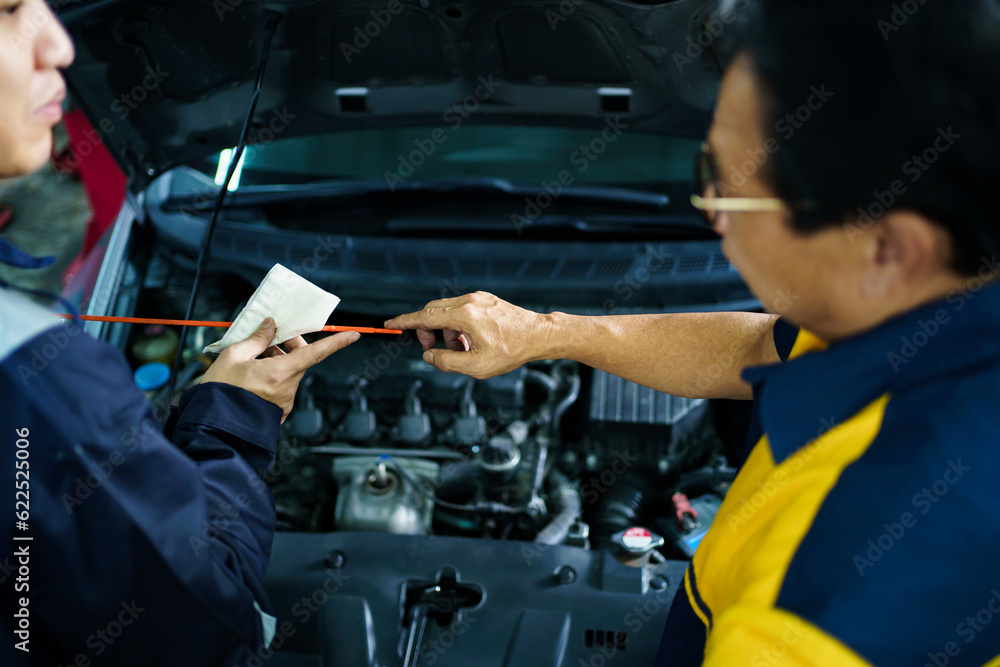 Team of vehicle technicians checking and measuring a vehicle oil engine ...