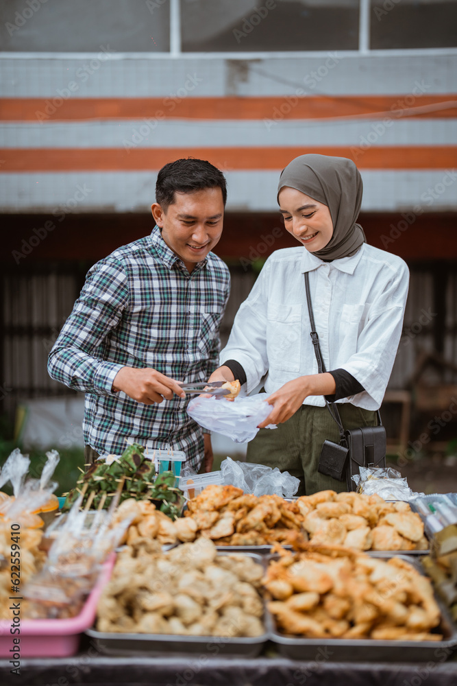 beautiful muslim couple are shopping in a food stall or street vendor ...