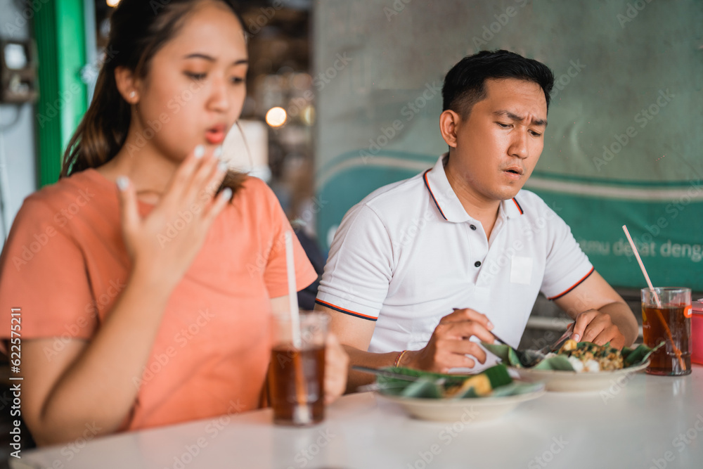 handsome man with a spicy expression eating pecel with Asian woman at a ...