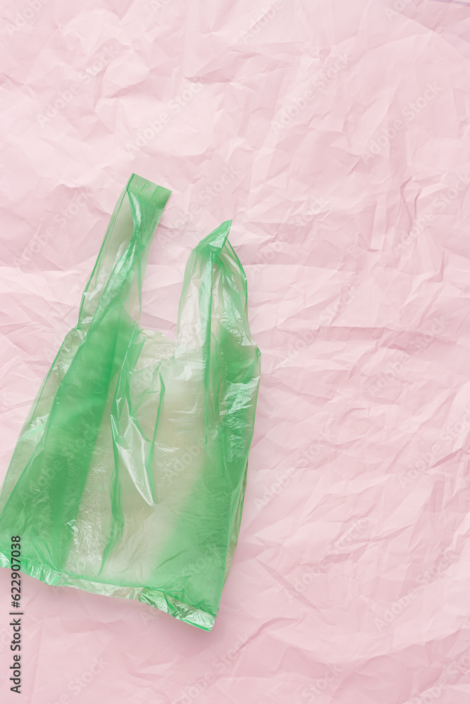 Plastic free concept, top view one green crumpled plastic bag on pink ...