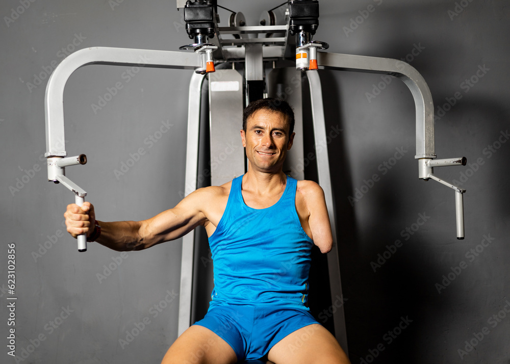 An adult bodybuilder with an amputated arm is sitting working the ...