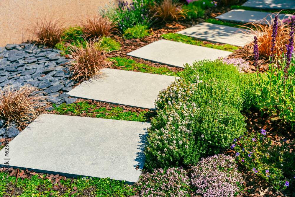 Detail of garden path with stone slabs with bark mulch and native ...