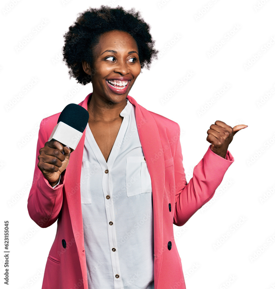African american woman with afro hair holding reporter microphone pointing thumb up to the side ...
