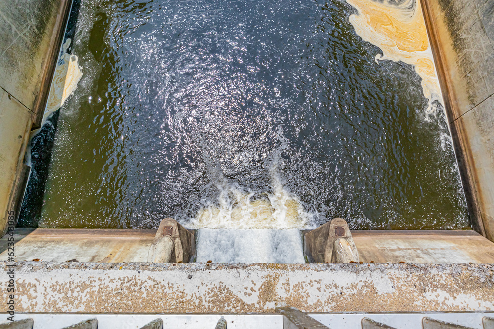 Gate of Staumauer Bitburger dam with water flowing out into Prum river ...