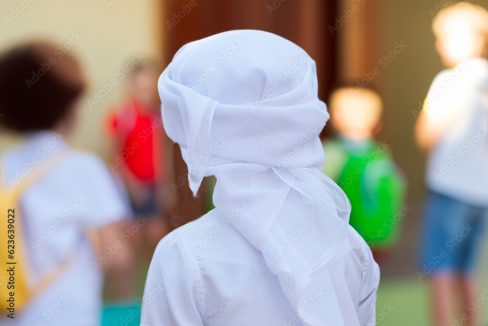 Backshot of boy in Ghutra Kandura at school with classmates. Emirati ...