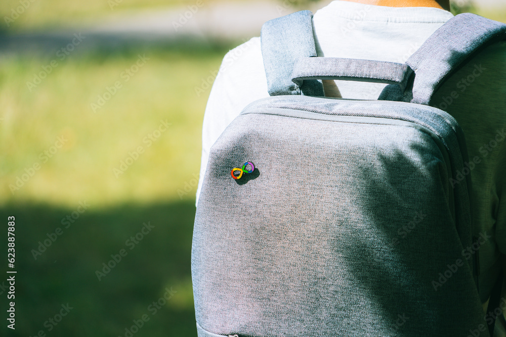 Foto Teenage boy with gray backpack with autism infinity rainbow symbol ...