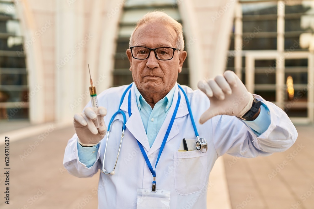 Senior doctor with grey hair holding syringe with angry face, negative ...