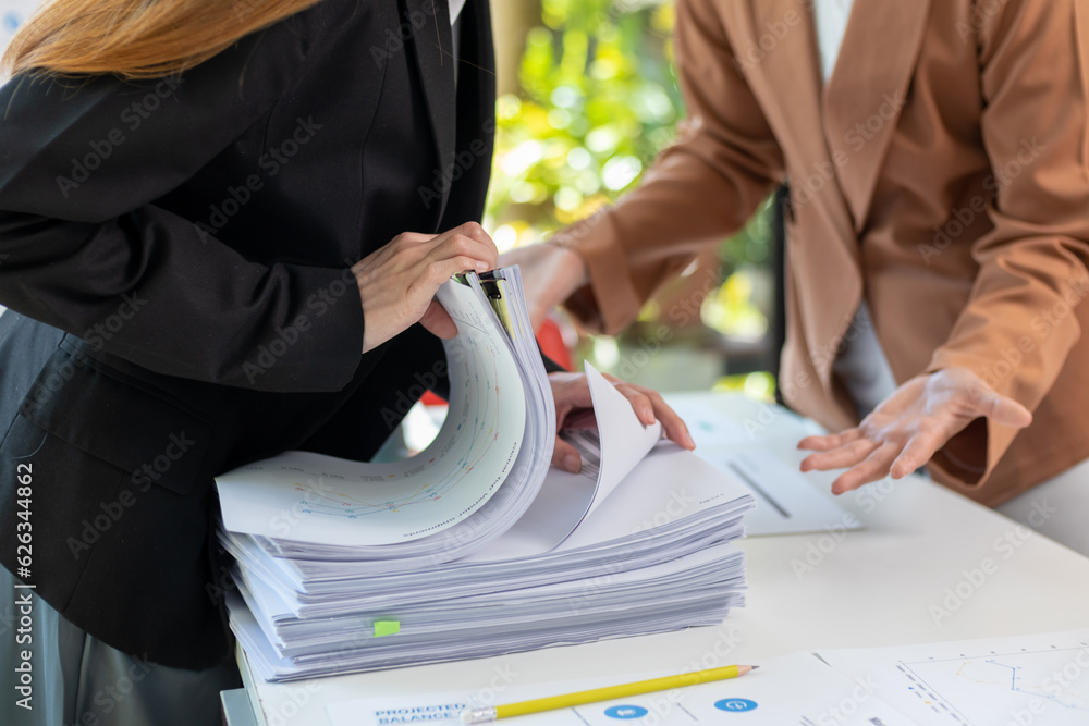 secretary searches through stacked paperwork on desk in office to find ...