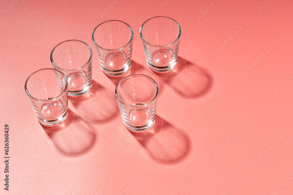 five glass glasses for alcohol on the surface. shadows from glasses ...