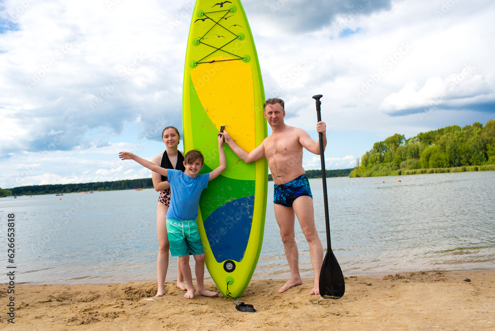 family posing with supboard on the background of the lake. a teenage ...