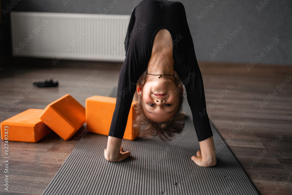Small girl doing bridge stand exercise in the training studio. Yoga for ...