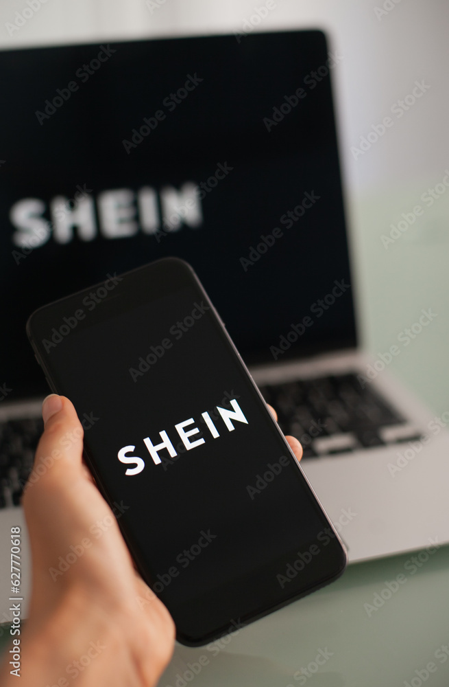 Shein logo on the screen of mobile phone. Hand holding smartphone. Fast ...