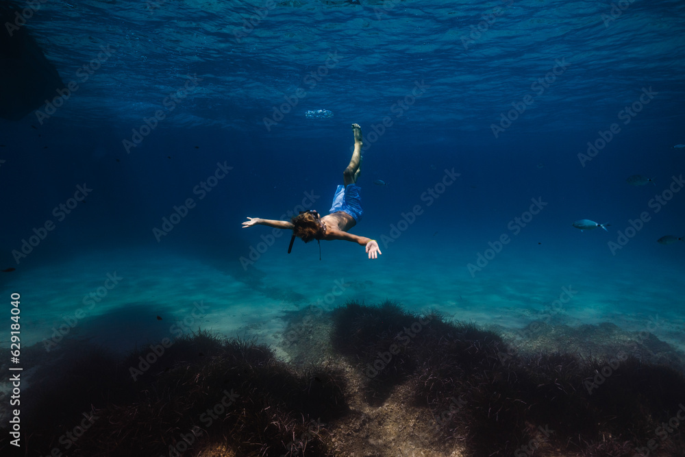 Boy swimming underwater in sea Stock Photo | Adobe Stock
