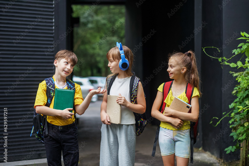 Three school children talking outdoors. Classmates with backpacks ...