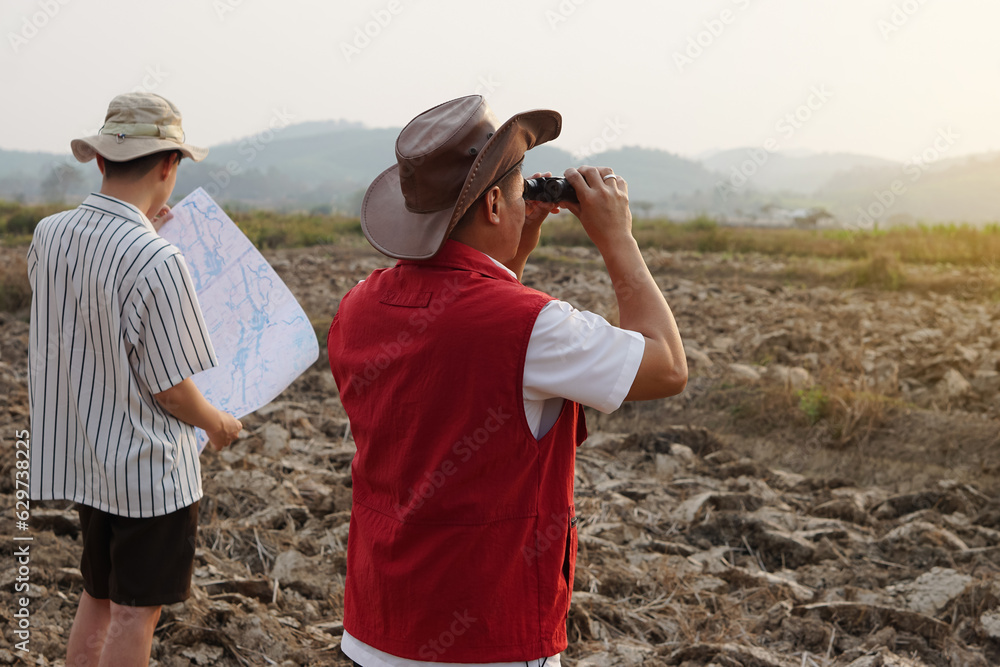 Asian man explorer wears hat, red vest shirt, holds binocular to ...