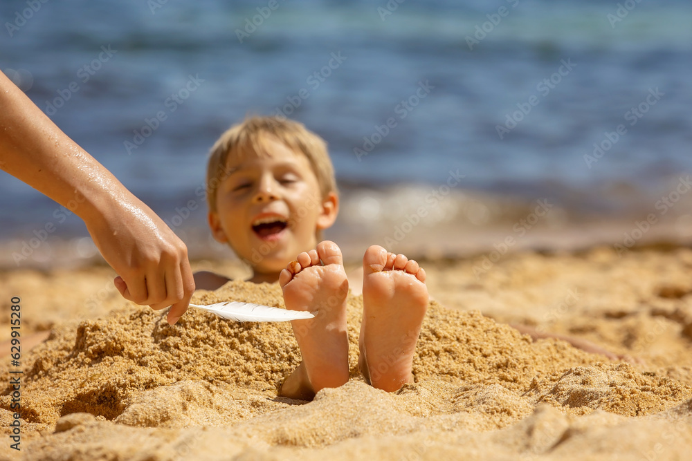 Child, tickling sibling on the beach on the feet with feather, kid ...