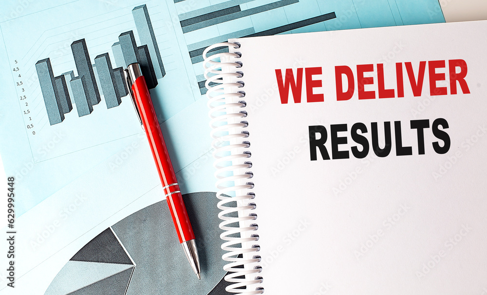 WE DELIVER RESULTS text on a notebook with pen on a chart background ...