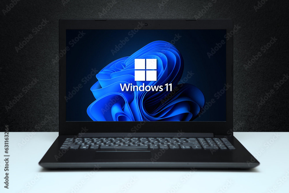 Windows 11 logo on the screen laptop computer black textured wall with ...