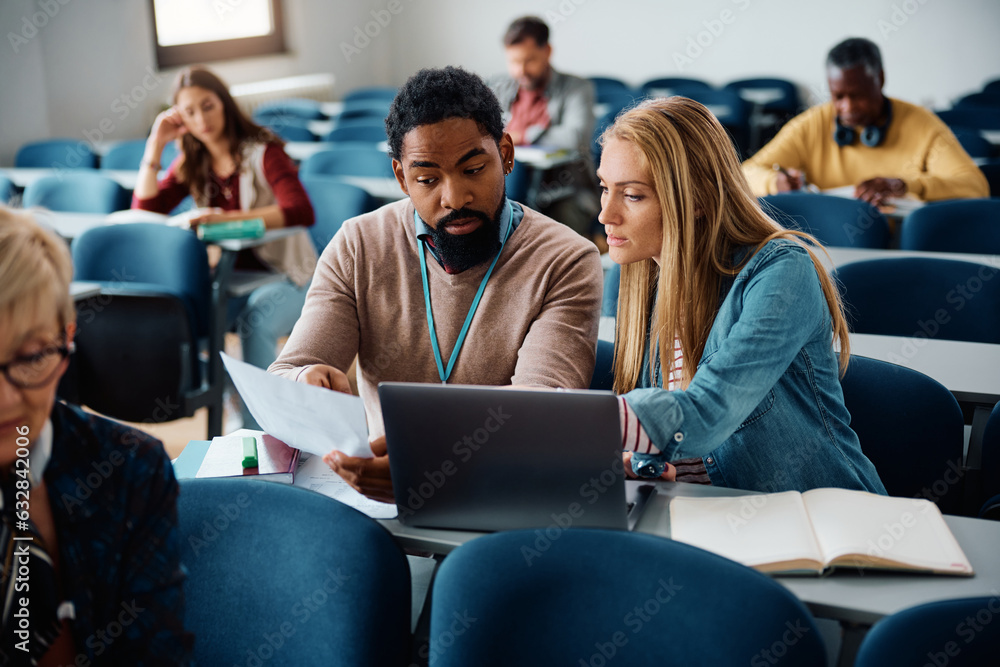 Black adult education teacher assists his student with an assignment ...