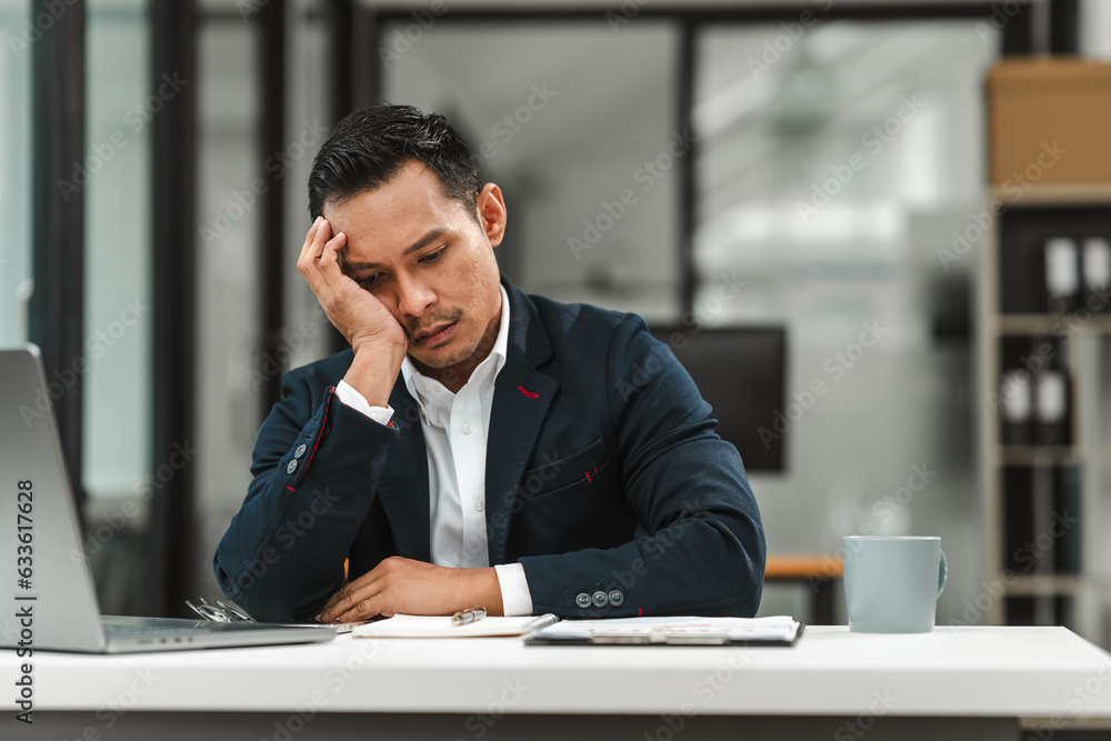 Asian businessman of Indian descent overworked in the office feeling ...
