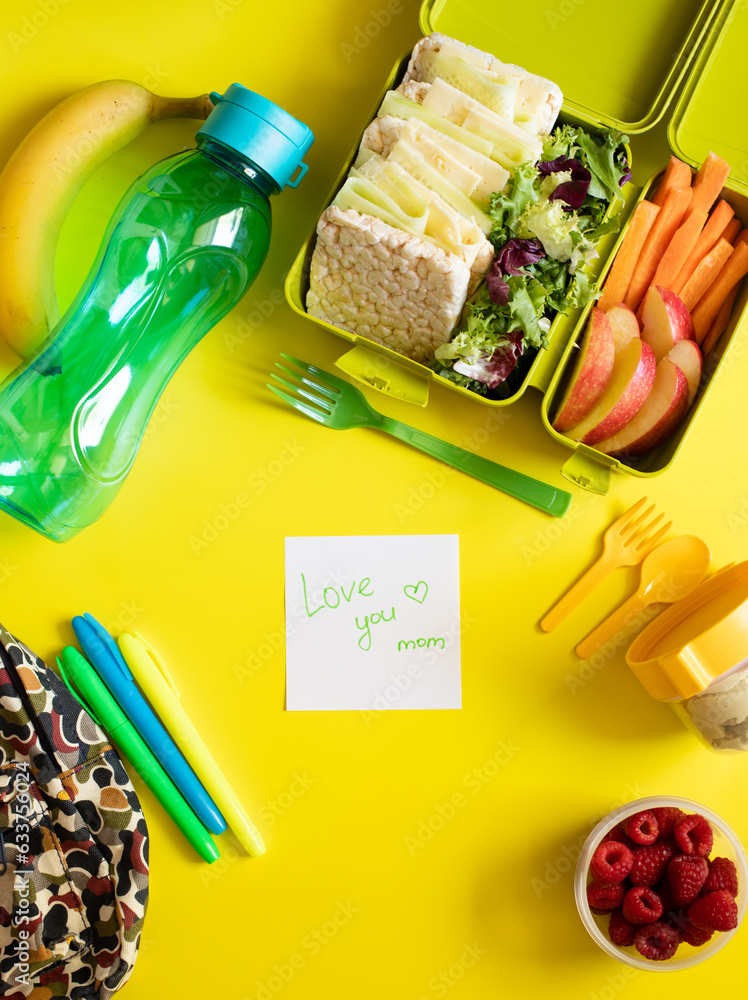 School lunch box with sandwiches, carrot sticks, apple, banana, lettuce ...