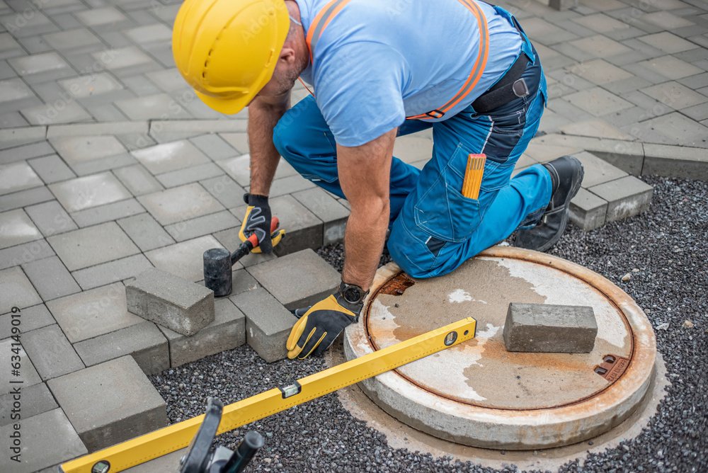 Laying interlocking paving. A worker is placing interlocking paving ...