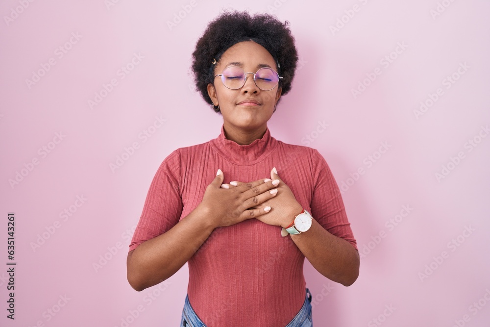Beautiful african woman with curly hair standing over pink background ...