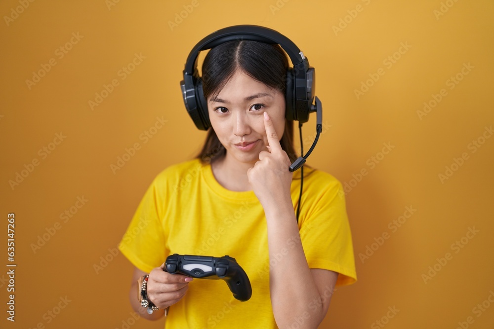 Chinese young woman playing video game holding controller pointing to ...